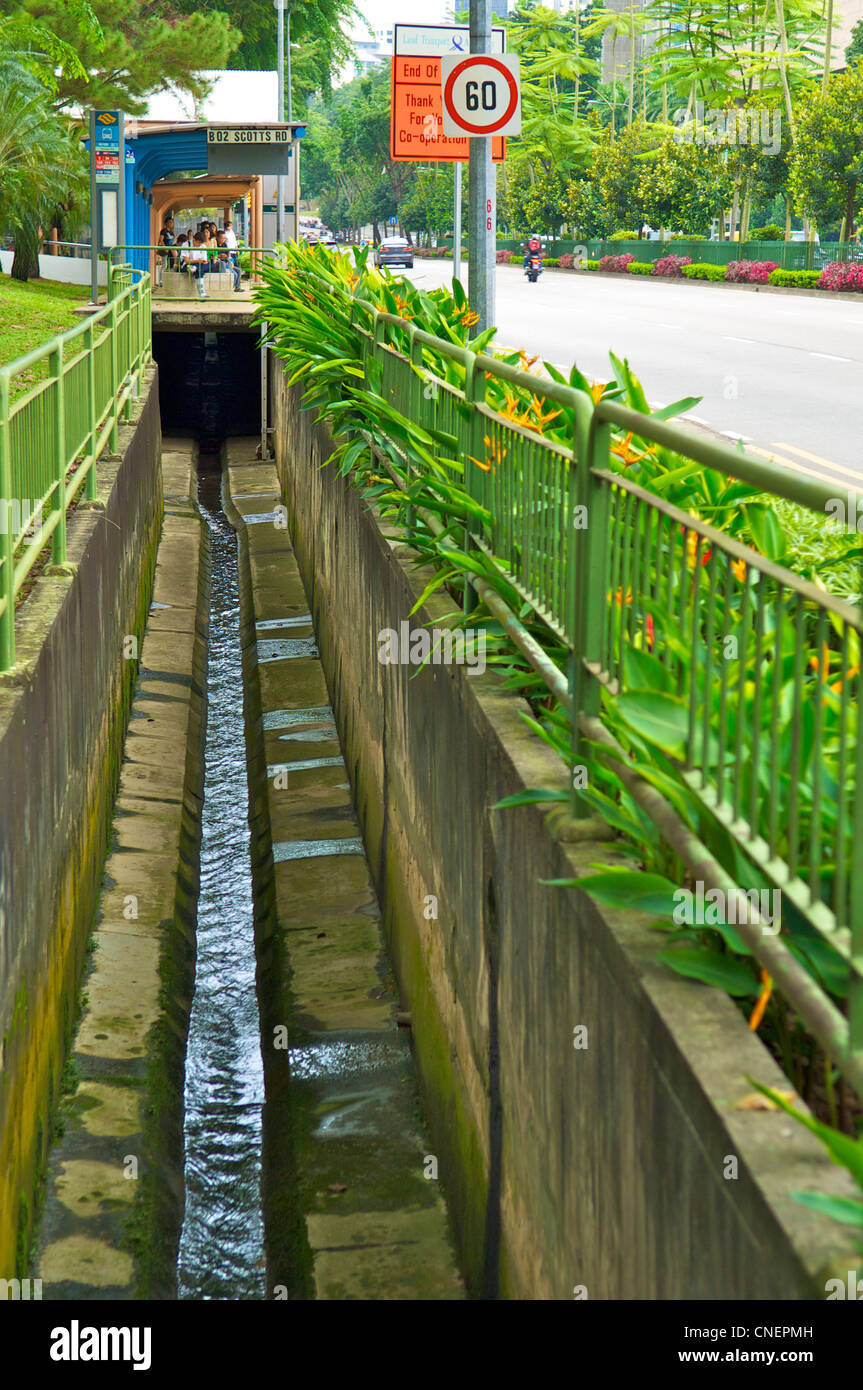 Open rain waste water sewerage under bus stop in central Singapore ...