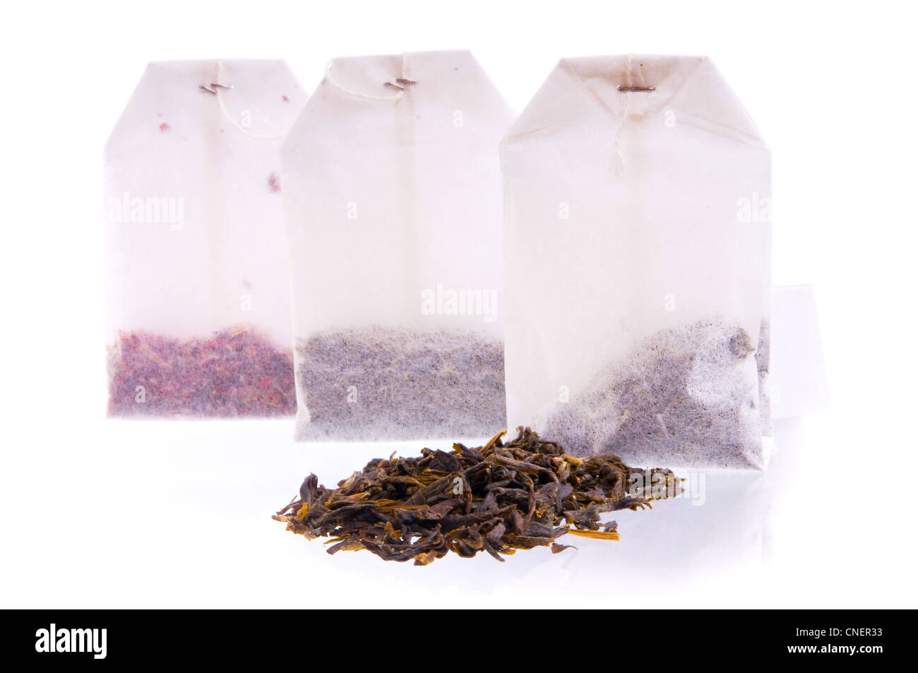 Three teabags with dry tea and heap of black tea. Focus on a first ...