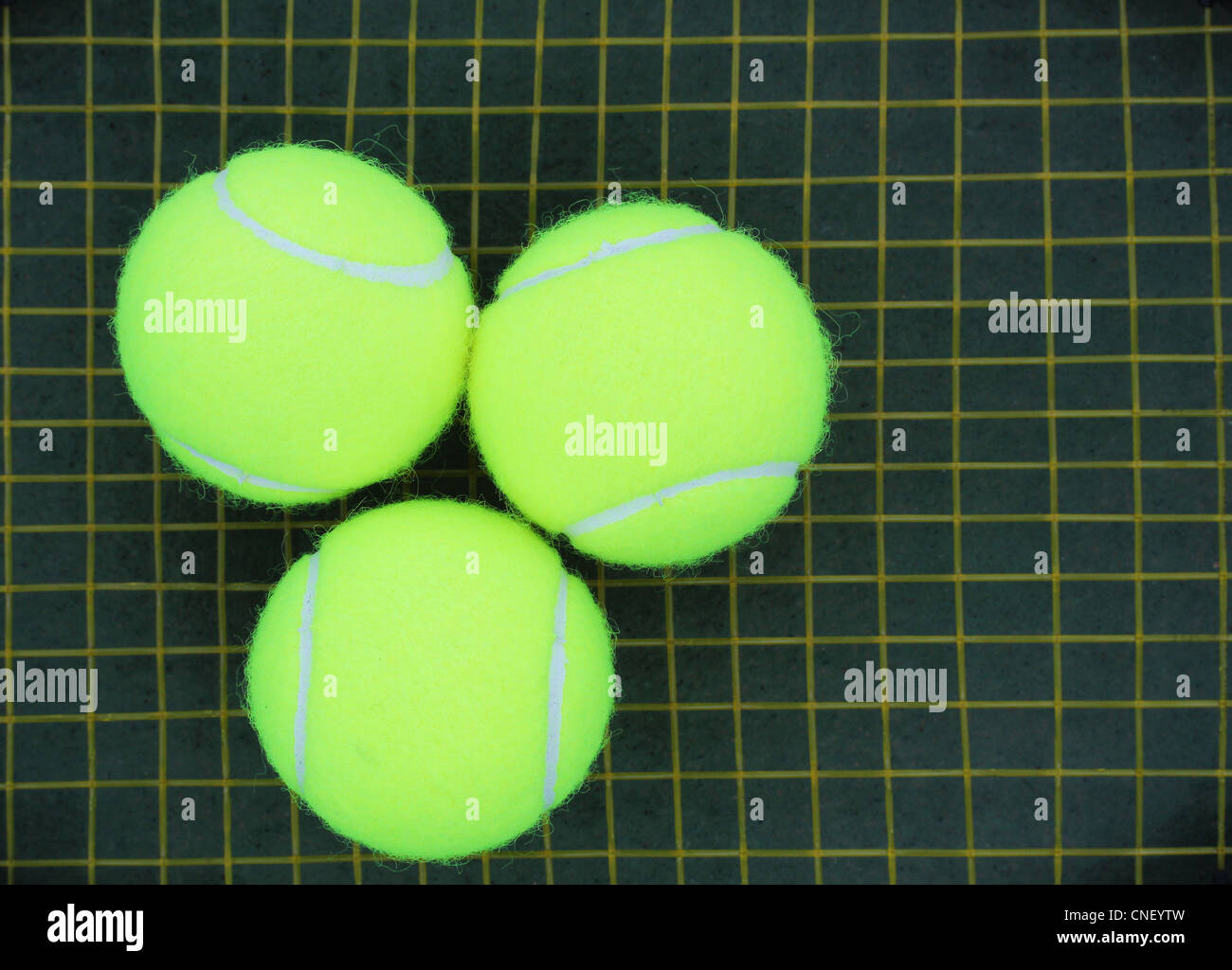 Three tennis balls placed on a racket strings in the background Stock ...