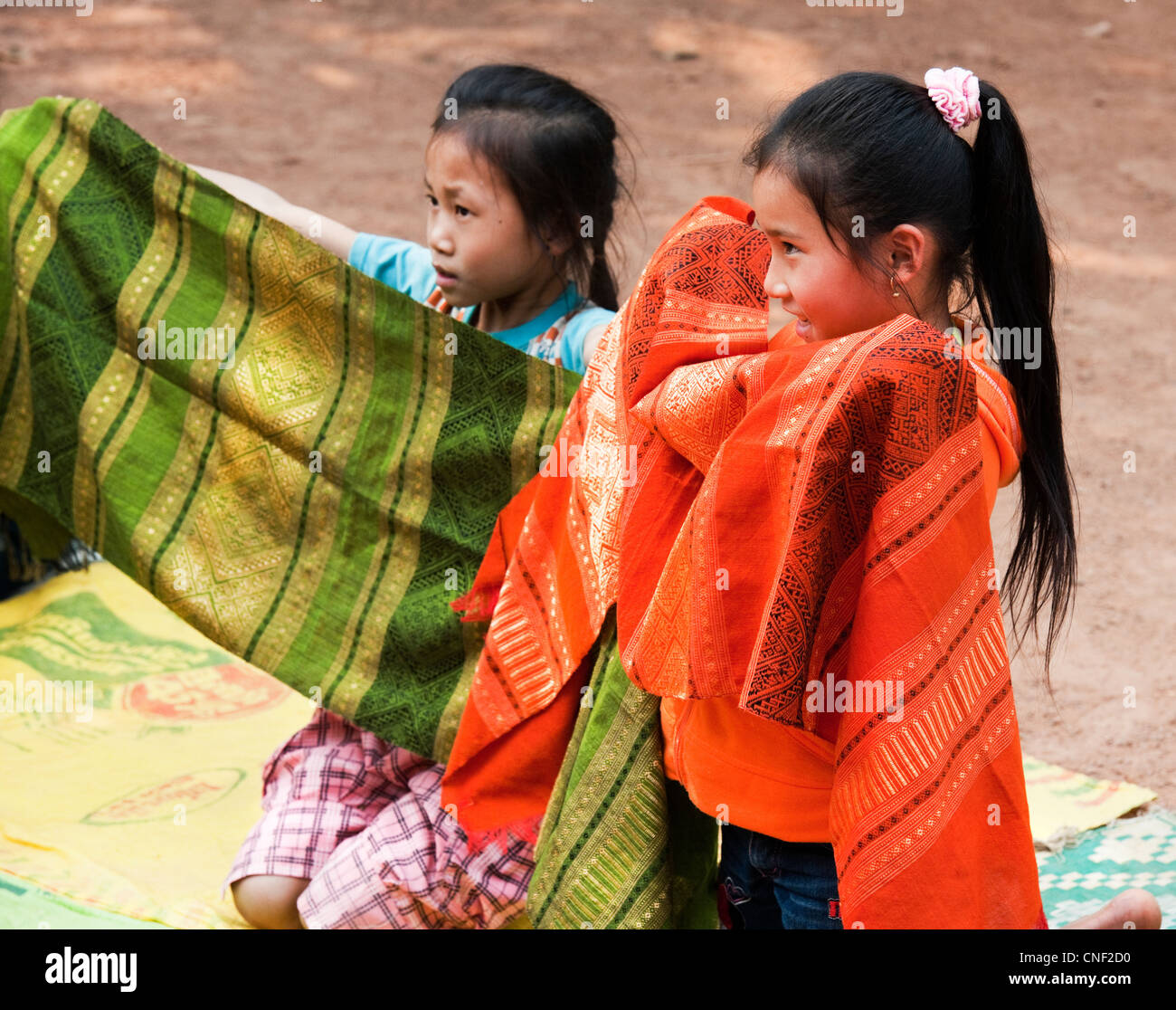 Two young Lao girls selling local crafts to Western tourists in a ...