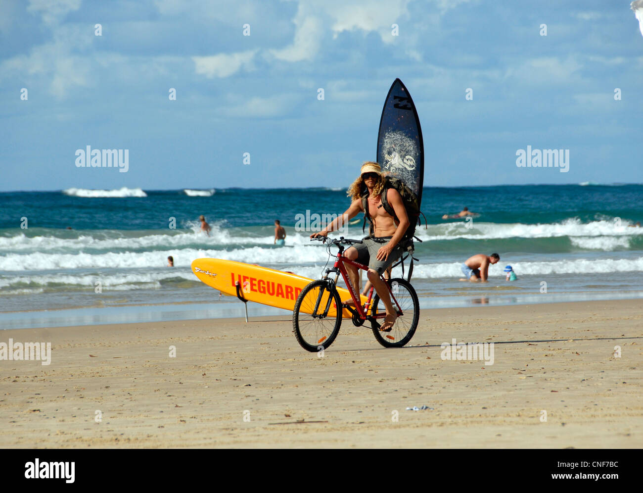 Surfer with surf board on back of his bike on Byron Bay main beach, NSW ...