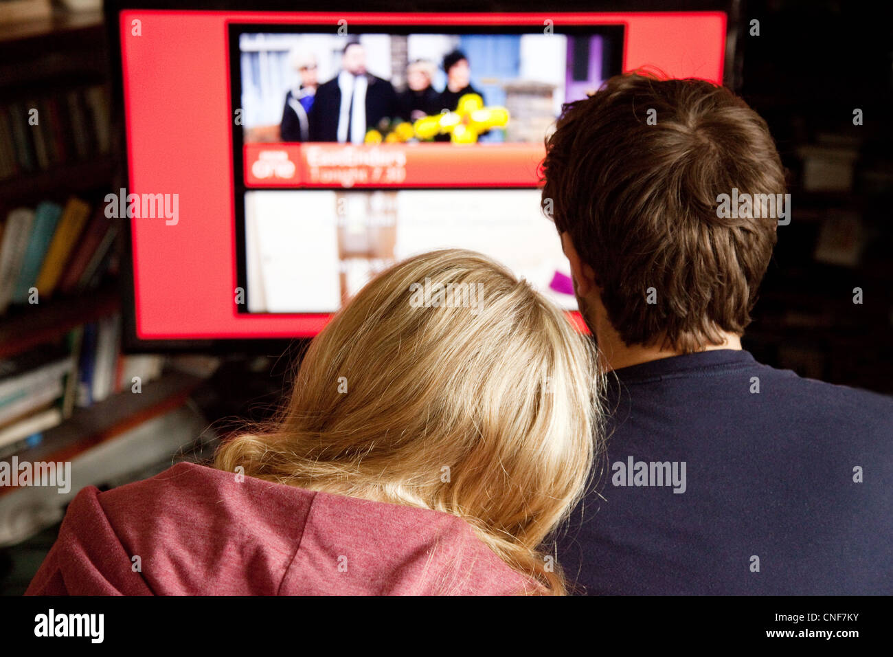 Rear view of young couple watching TV television on a large screen, UK ...