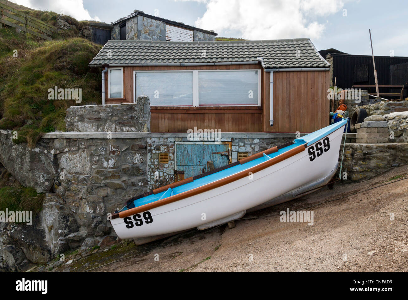 small fishing boat on slope next to small hut Stock Photo - Alamy