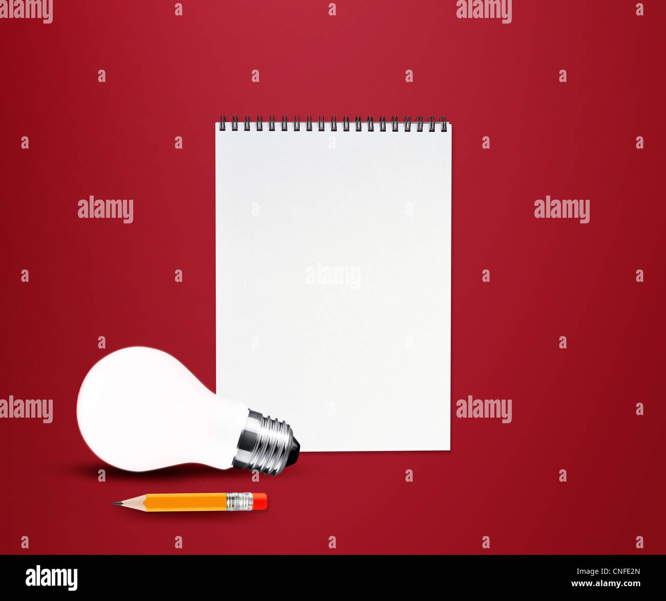 pencils and notepad and light bulb on red background Stock Photo - Alamy