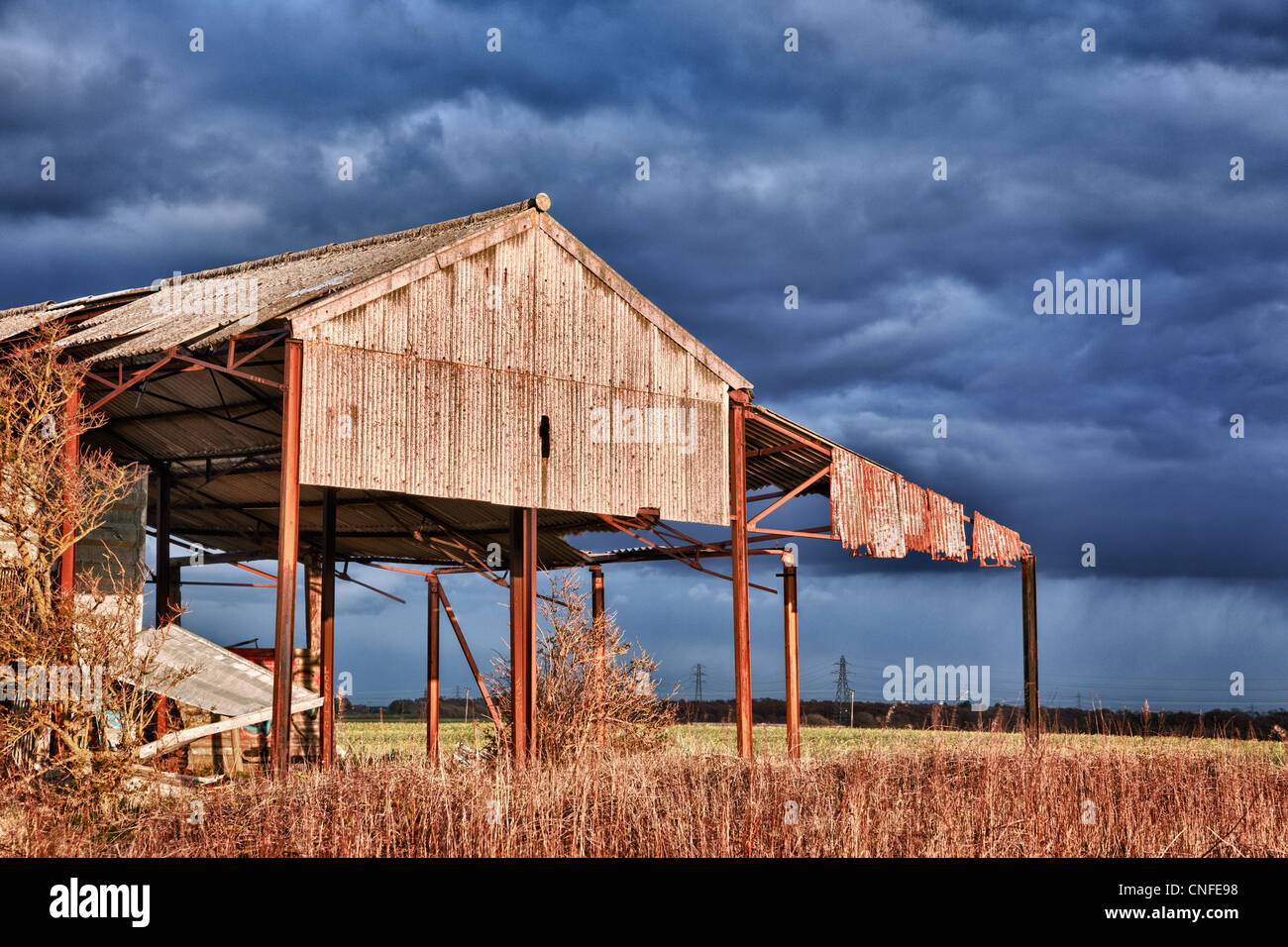 Storm clouds over sunlit deserted and ruined barn on farmland Stock ...