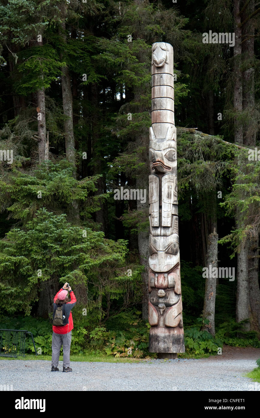 Woman takes a photo of Tlingit totem pole at Sitka National Historical ...
