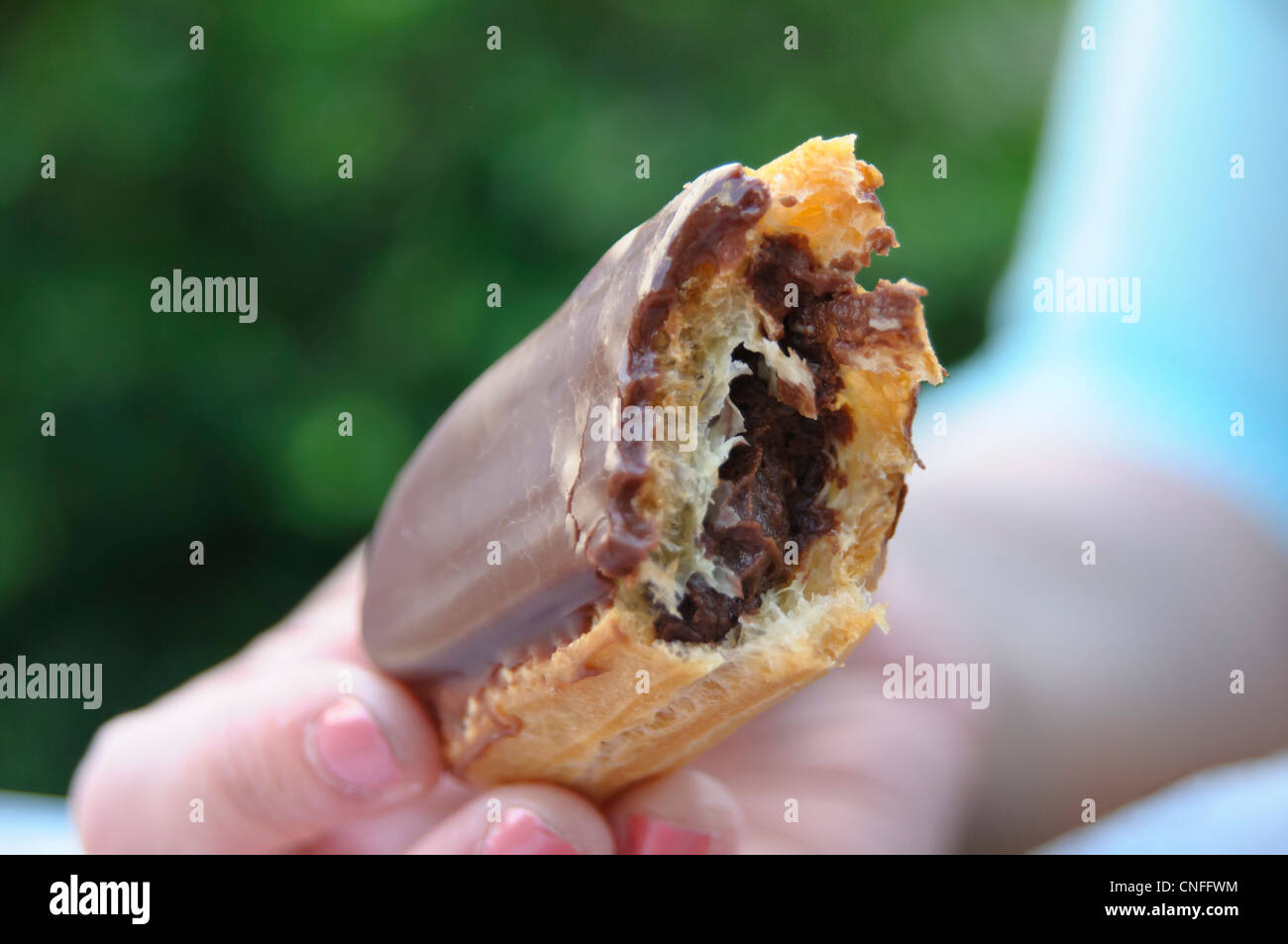 Woman's hand holding a chocolate eclair from a patisserie on Rue Clear ...