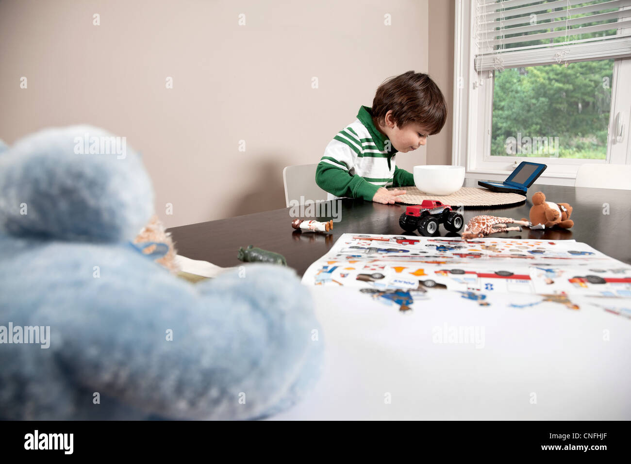 Boy at table with bowl of food and toys Stock Photo - Alamy