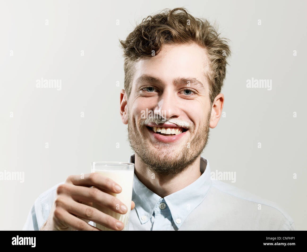 Young man smiling with milk moustache, studio shot Stock Photo - Alamy
