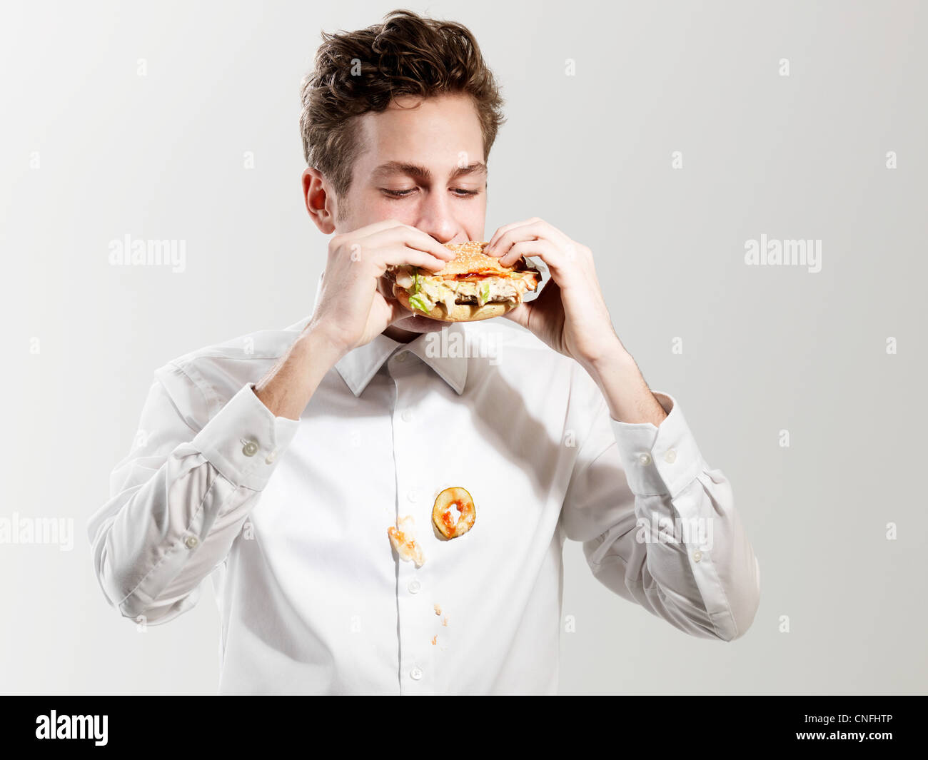 Young man eating messy sandwich, studio shot Stock Photo - Alamy