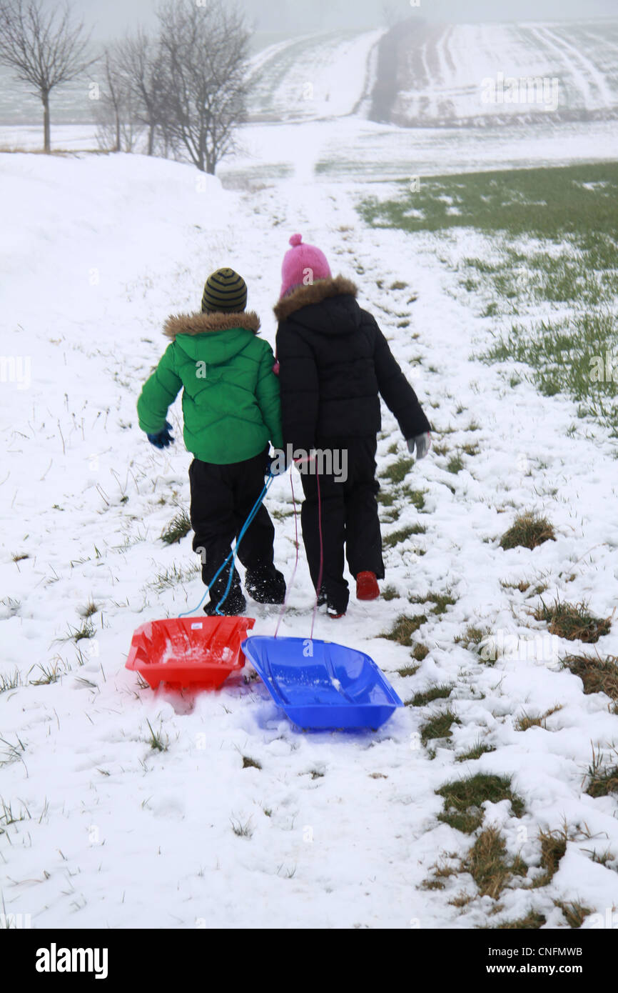 Two children pulling sledges hi-res stock photography and images - Alamy