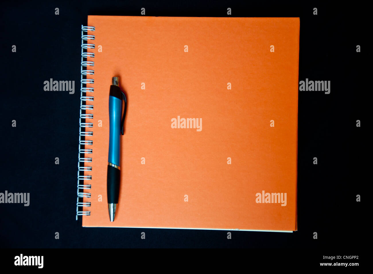 orange notebook and pen on black background Stock Photo - Alamy