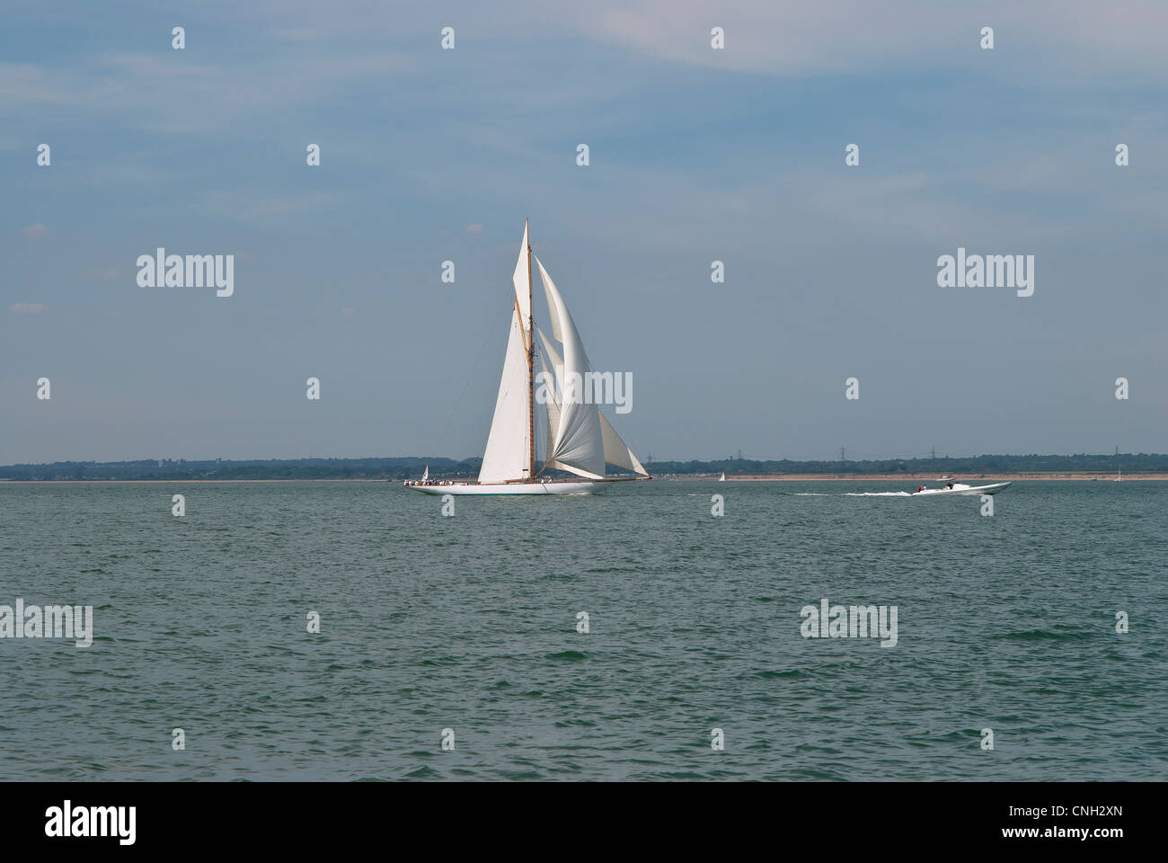 Single mast schooner sailing off southampton, england with a speed boat ...