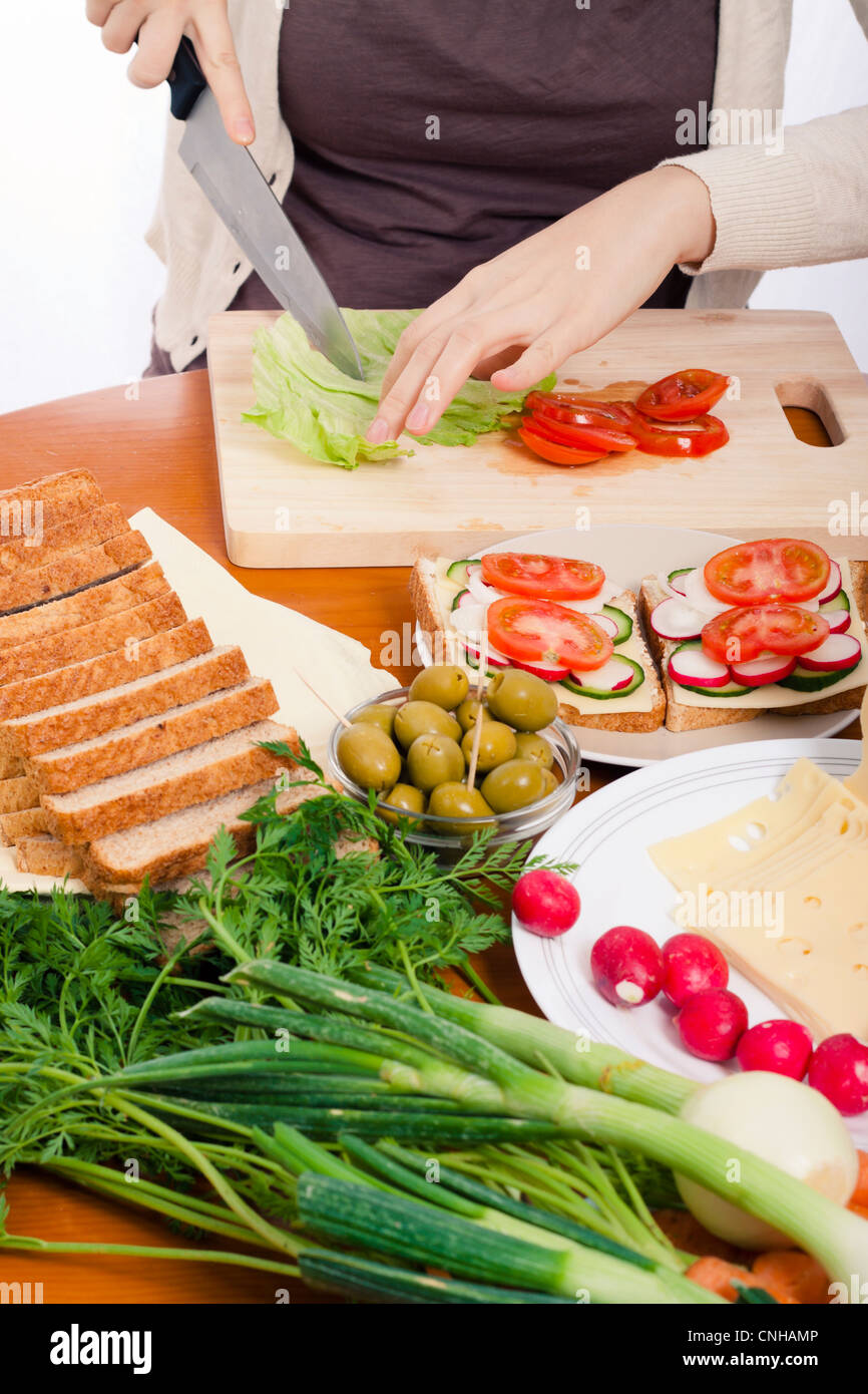 Detail of kitchen table and woman cutting fresh vegetable and making ...