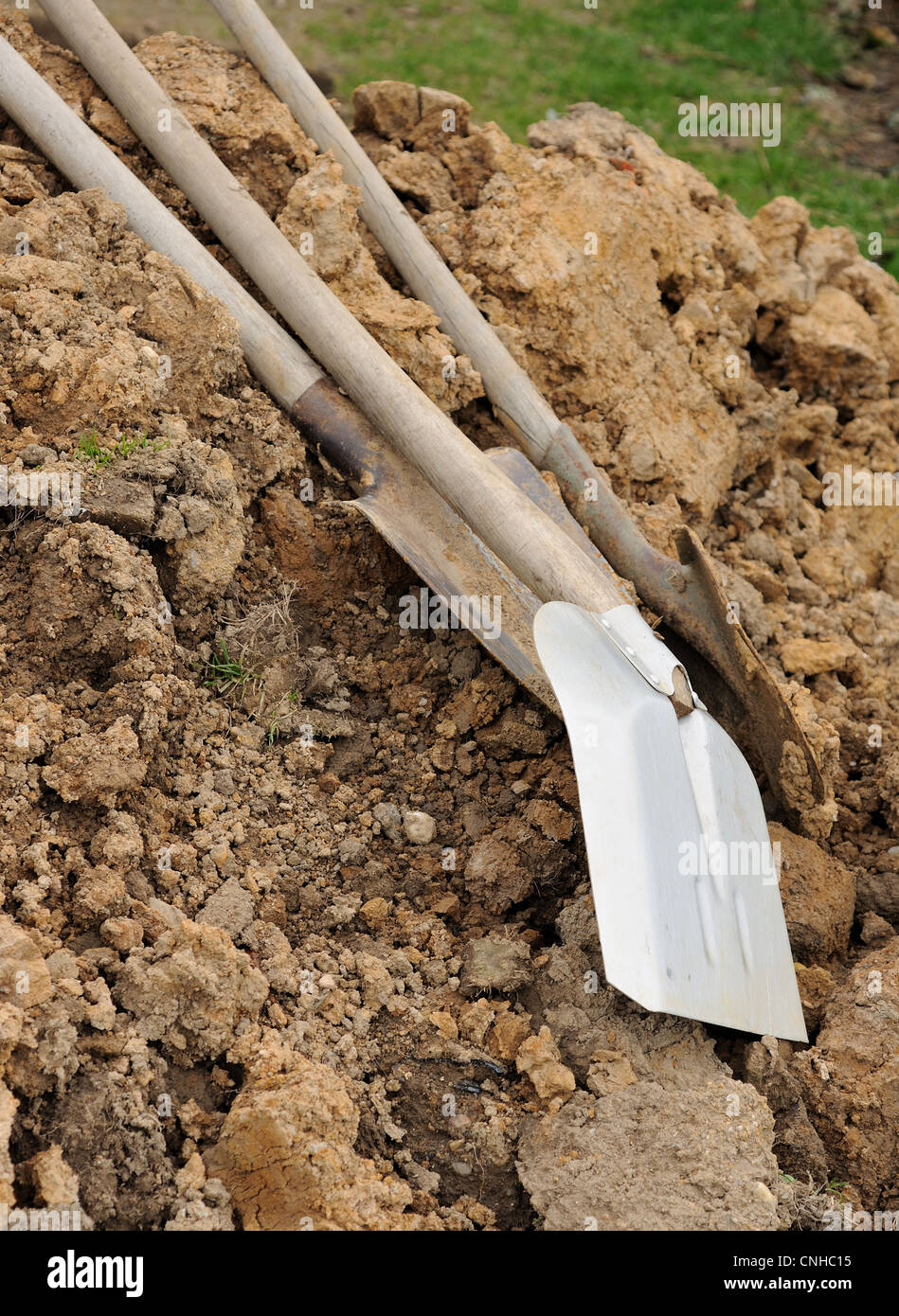 Shovel and spades placed on the big soil heap Stock Photo - Alamy