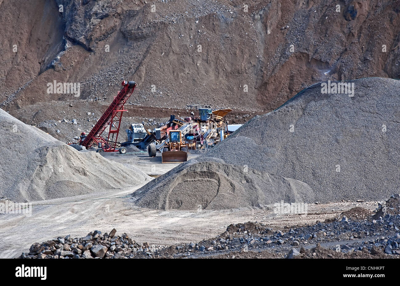 Heavy equipment trucks, cranes and other machinery in a large quarry ...