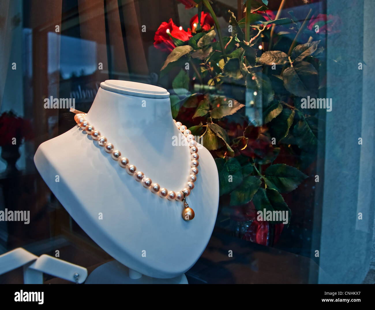 Pearl drop necklace store display with red roses with dramatic lighting ...