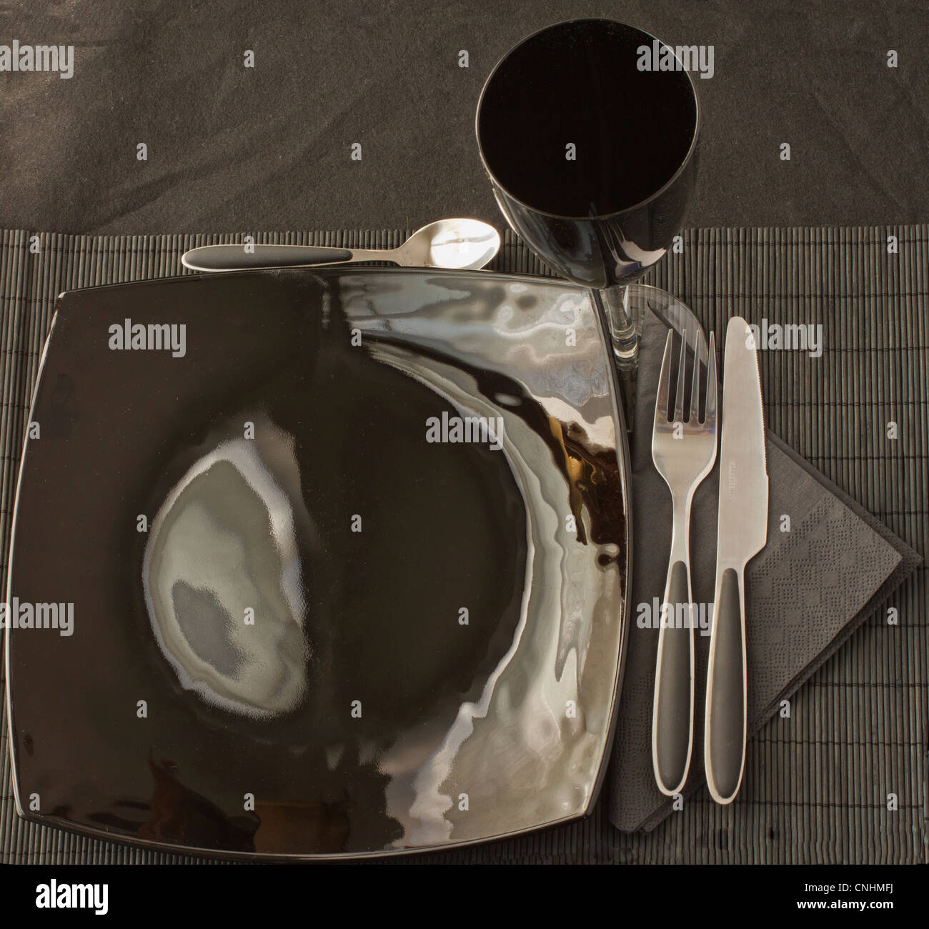 Black elegant plate and cutlery over black mat Stock Photo - Alamy
