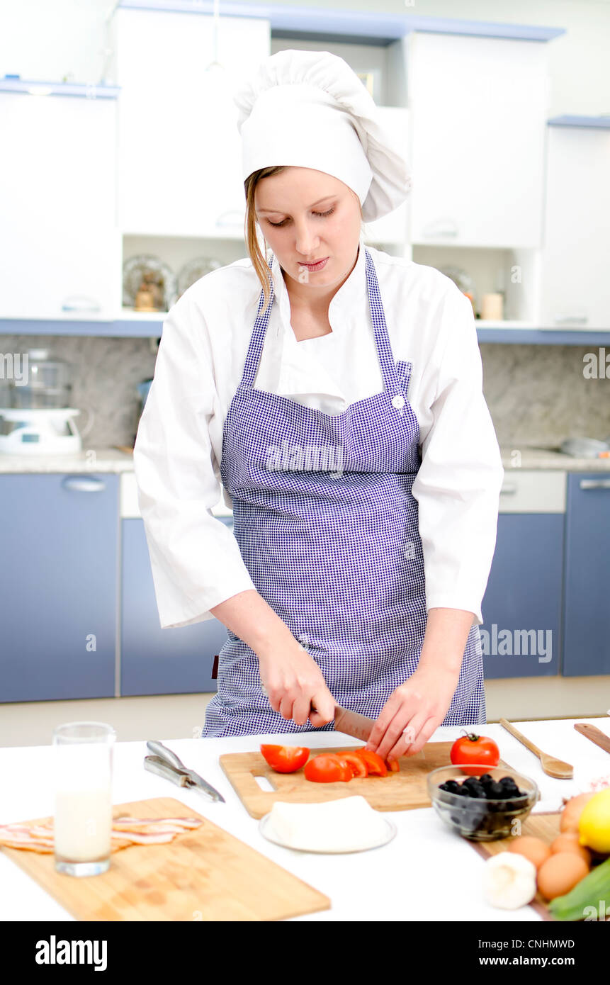Attractive chief cook preparing food , cutting tomatoes Stock Photo - Alamy