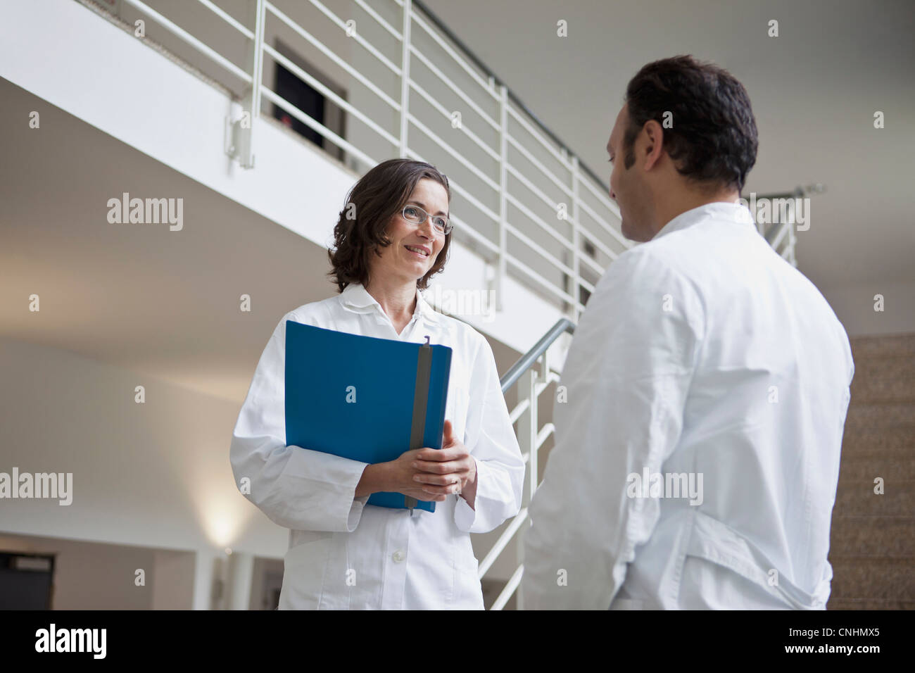 Two doctors talking on a staircase Stock Photo - Alamy