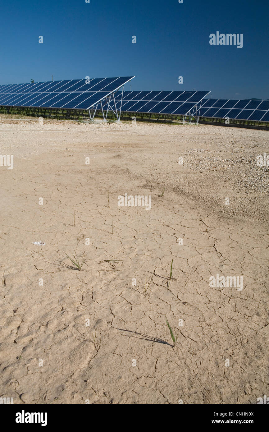 Dry ground next to rows of solar panels in a field Stock Photo - Alamy