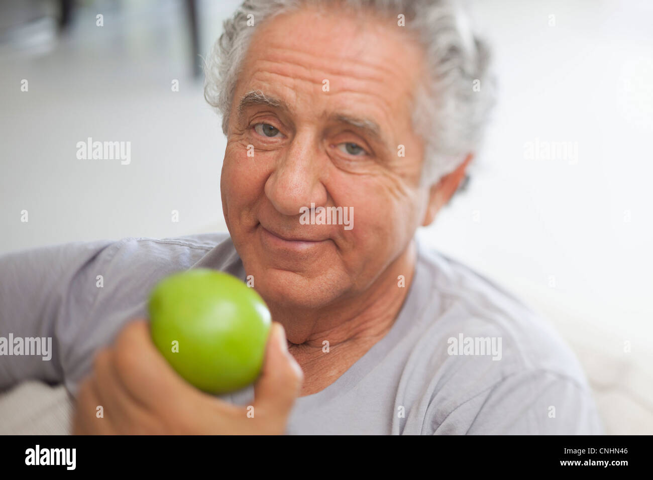 A senior man preparing to eat a green apple Stock Photo - Alamy