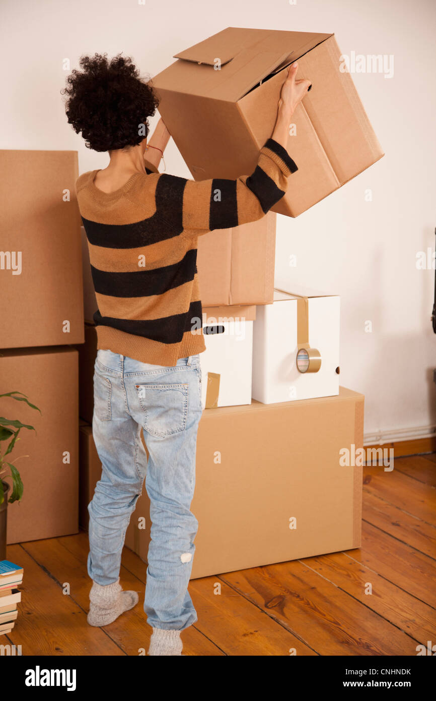 A woman lifting a moving box and placing on a stack of boxes Stock ...