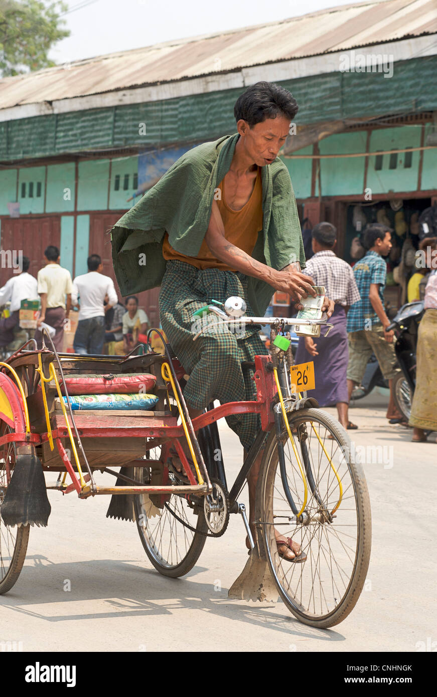 Burmese urban street scene - rickshaw driver counting his money. Pagan ...