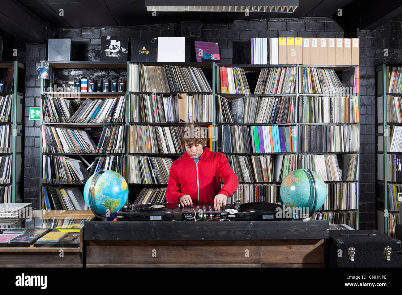 A young man using a sound mixer and DJ decks at a record store Stock ...