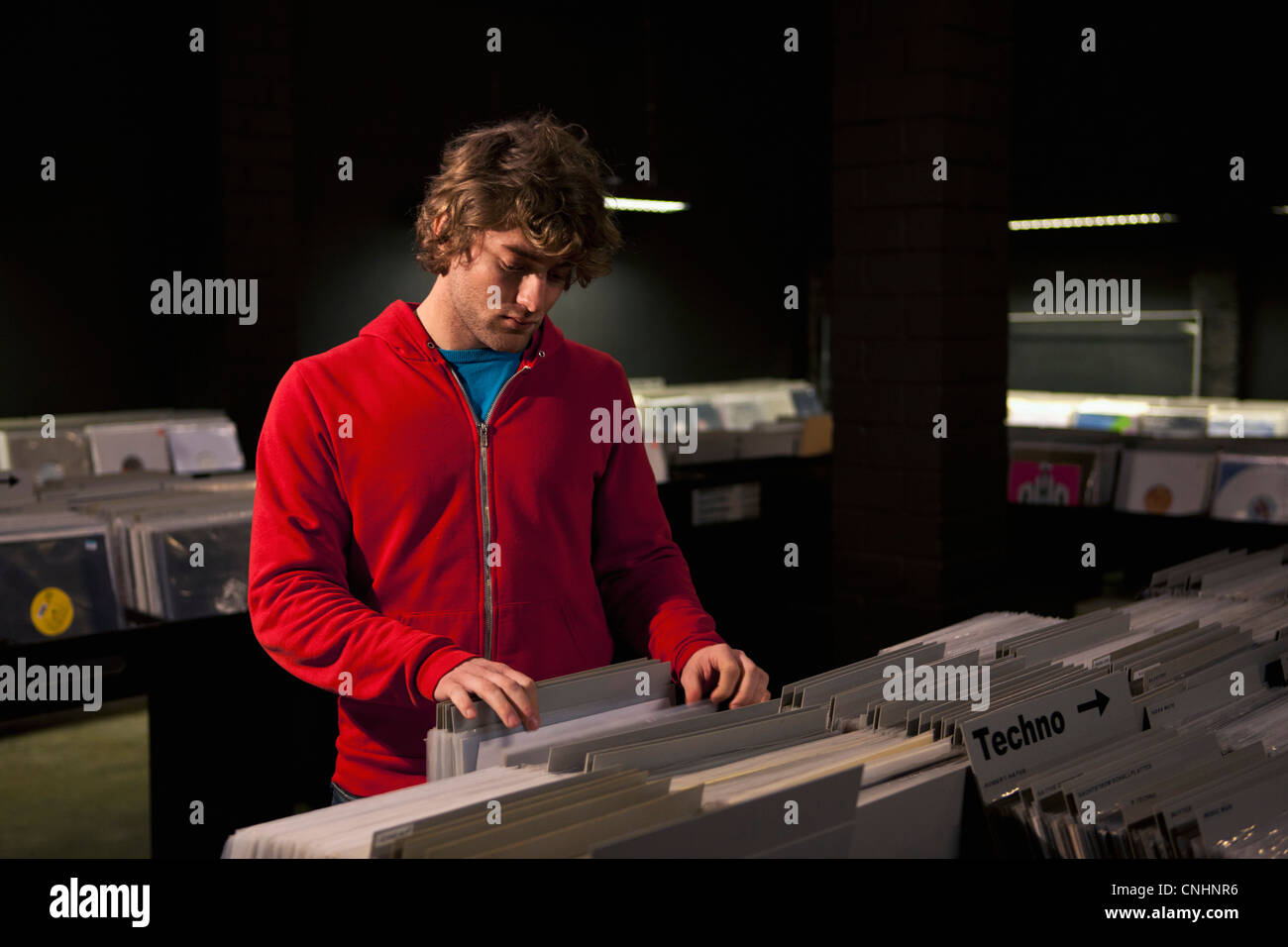 A young man searching through records in a darkened record shop Stock ...