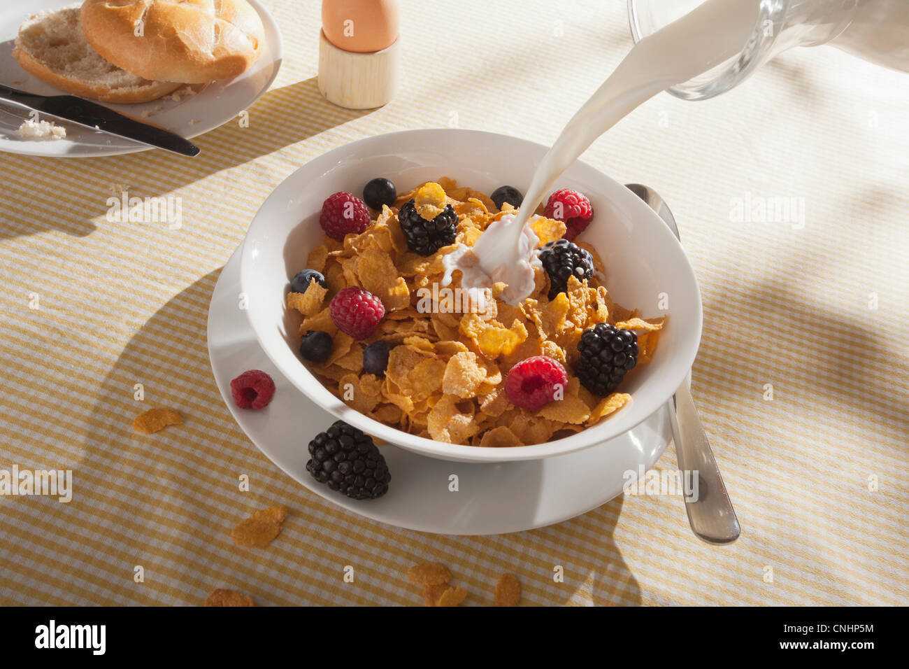 Milk being poured on a bowl of cornflakes with fruit Stock Photo - Alamy