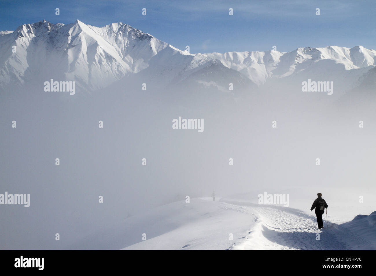 Hiking on trail by snowy mountain range Stock Photo - Alamy