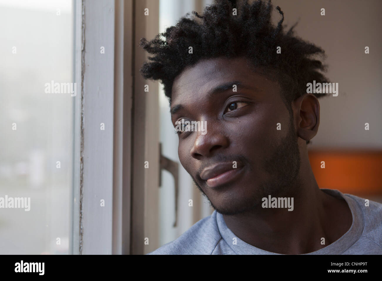 A young man looking out a window Stock Photo - Alamy