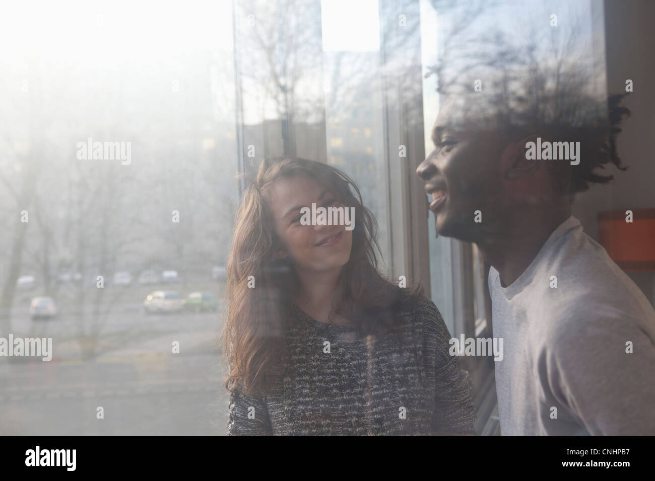 A boyfriend and girlfriend laughing together, viewed through window ...