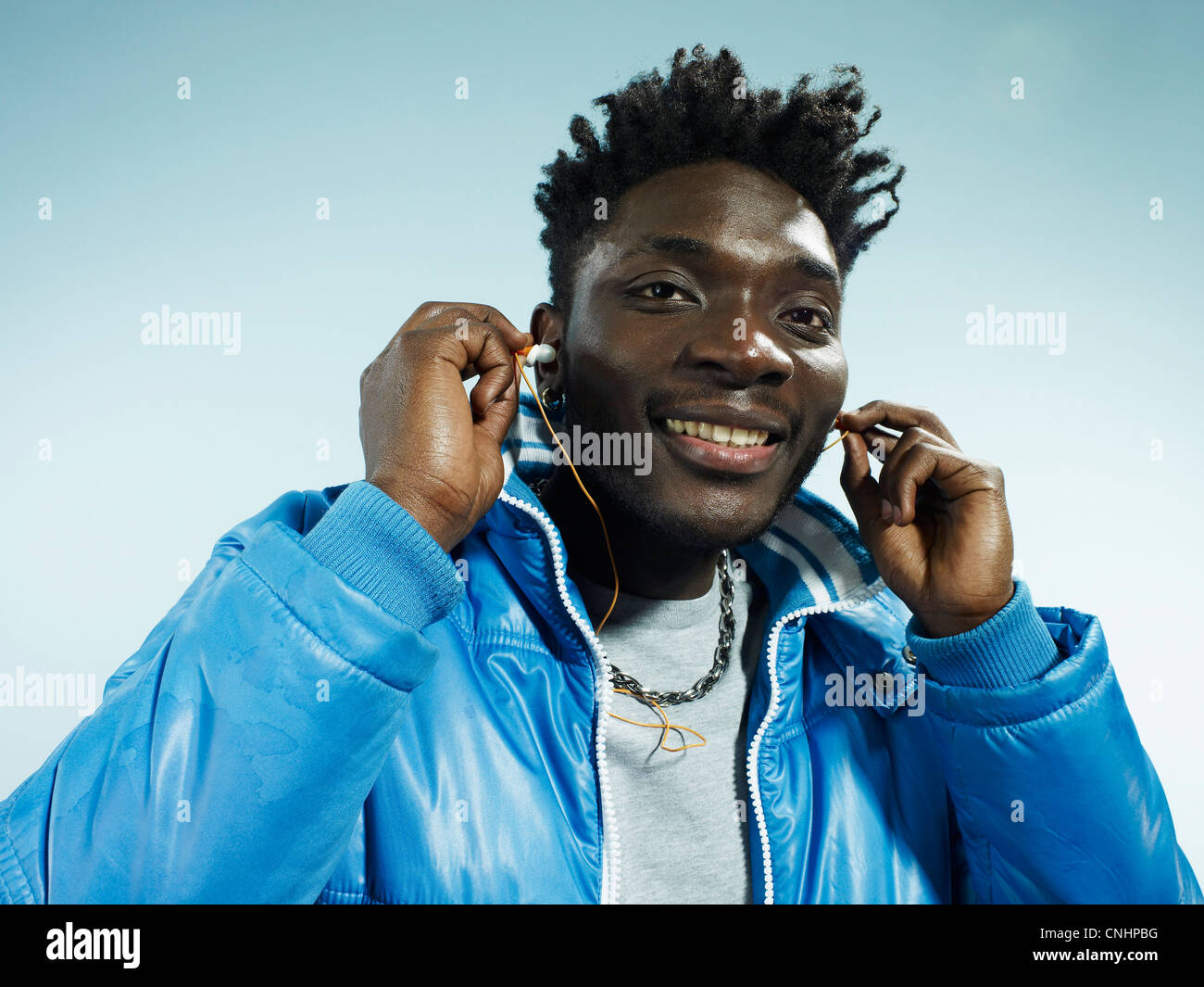 A young man wearing a vintage ski jacket and putting in earbuds Stock ...