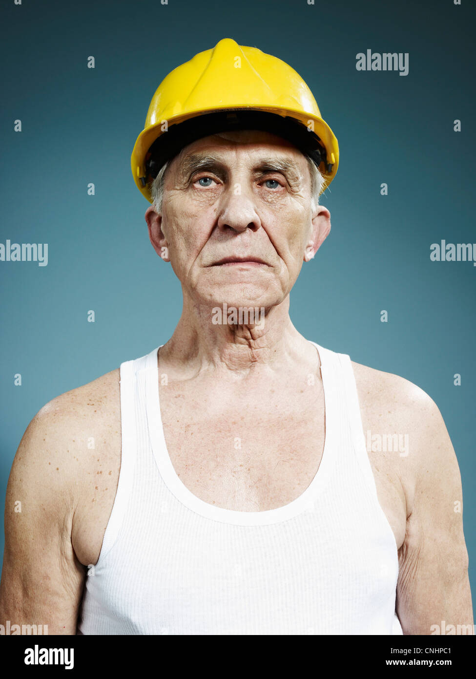 A serious senior man wearing a hardhat and tank top Stock Photo - Alamy