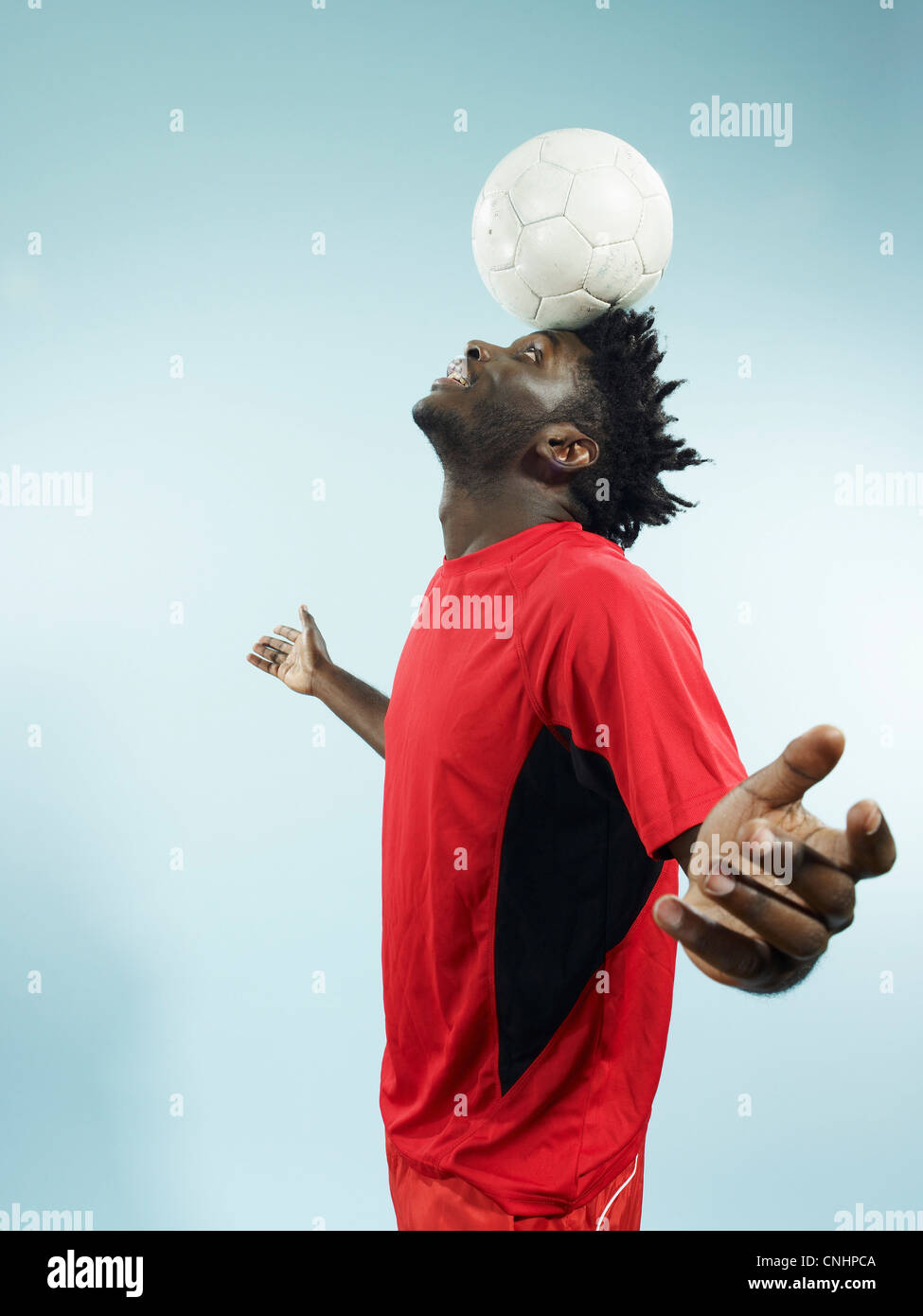 A young man balancing a soccer ball on her forehead Stock Photo - Alamy