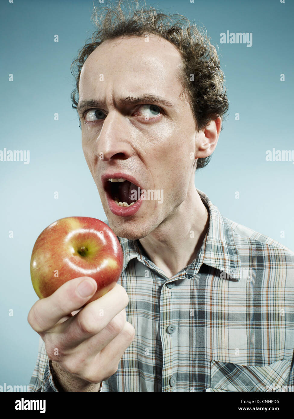A frowning man preparing to bite into an apple Stock Photo - Alamy