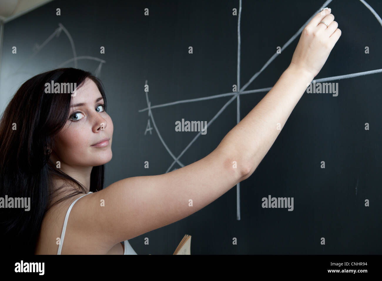 pretty young teacher drawing on the chalkboard/blackboard during a math ...