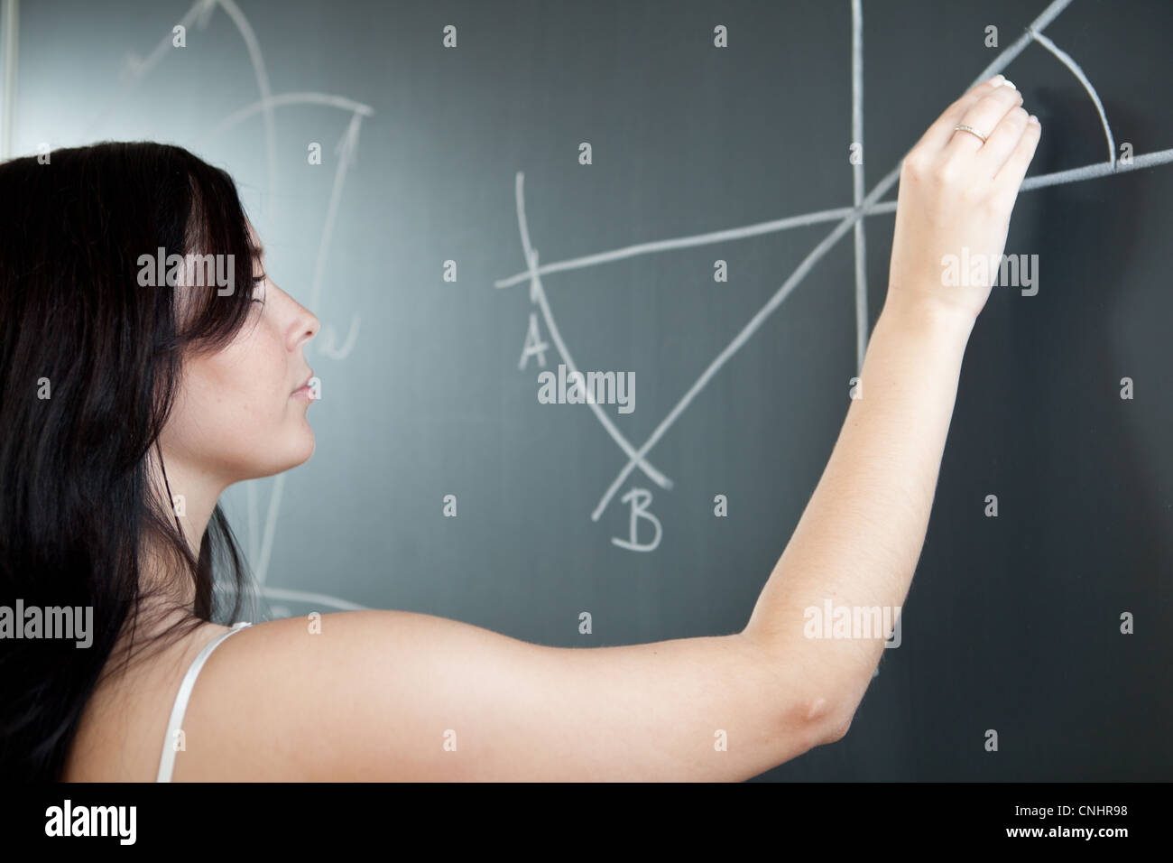pretty young teacher drawing on the chalkboard/blackboard during a math ...