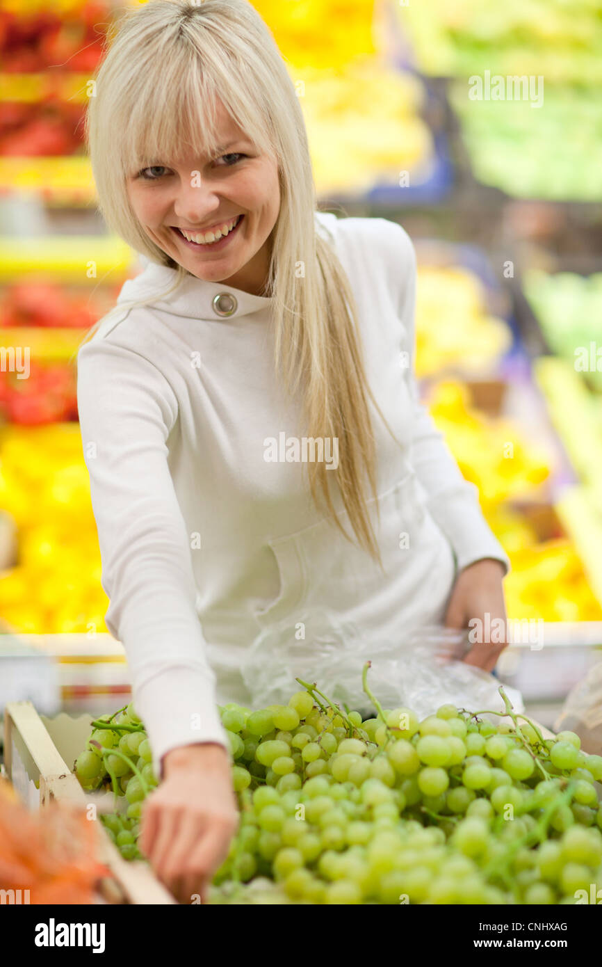 Beautiful young woman shopping for fruits and vegetables in produce ...