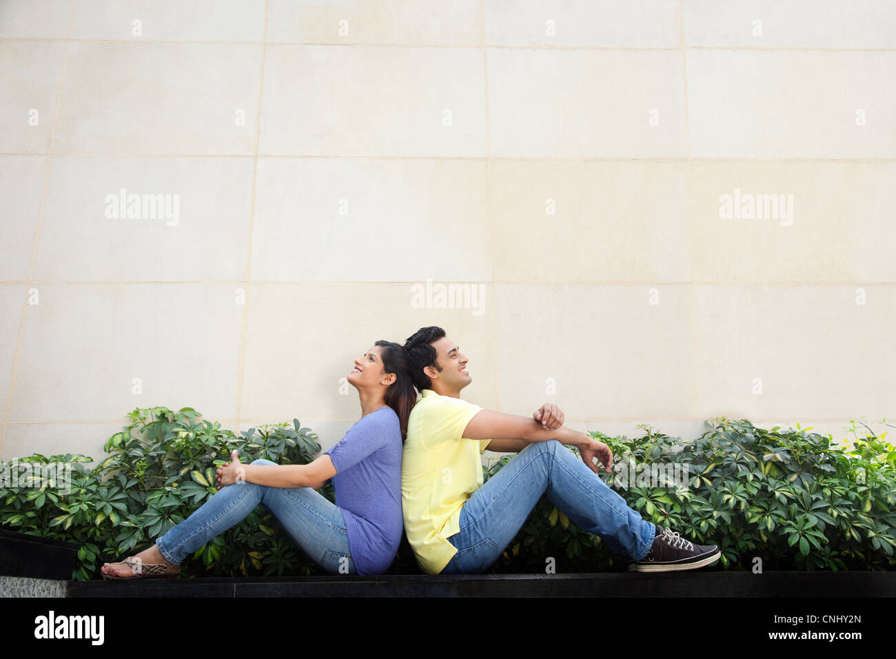 Couple sitting back to back Stock Photo - Alamy