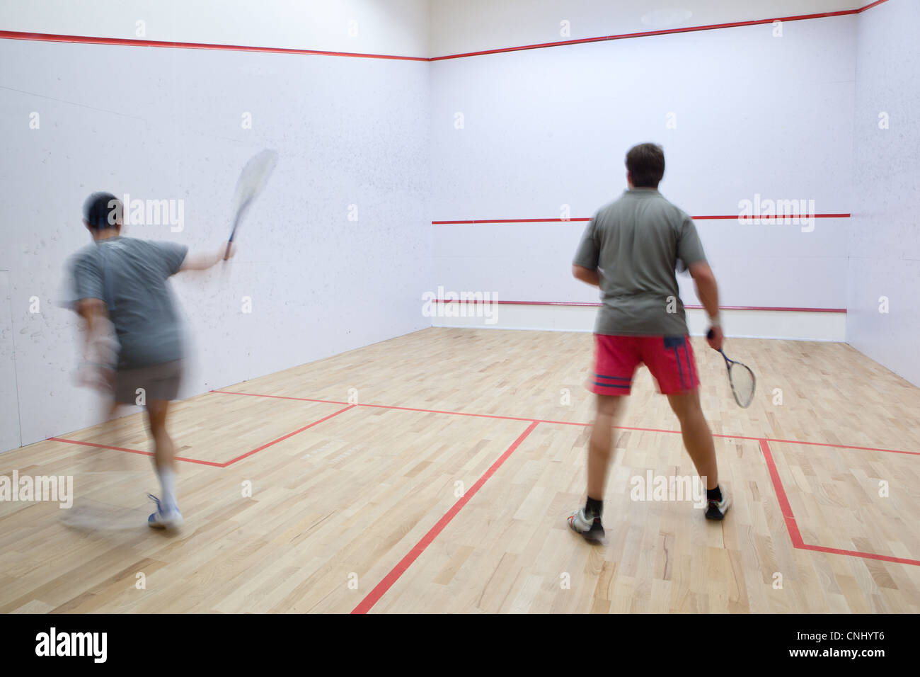 Squash players in action on a squash court (motion blurred image; color ...