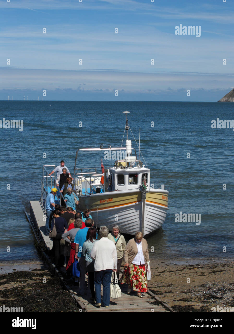 people waiting to get aboard a pleasure boat for trips round the bay of ...