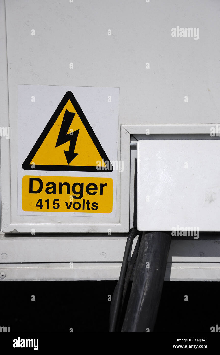 Yellow electrical hazard warning sign by plugged in electric cable ...