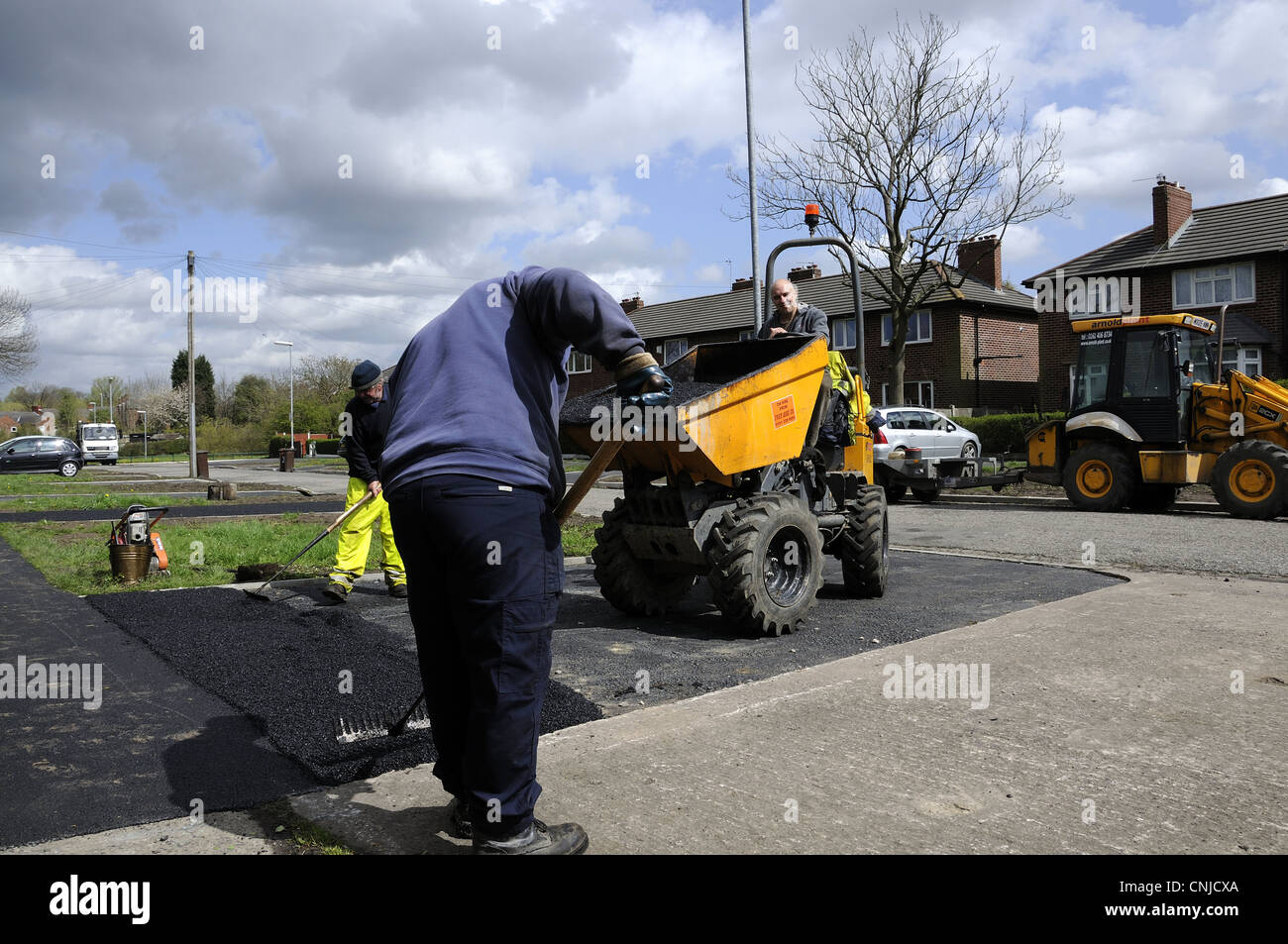 Dump truck ready to tip asphalt after previous load is raked and spread ...