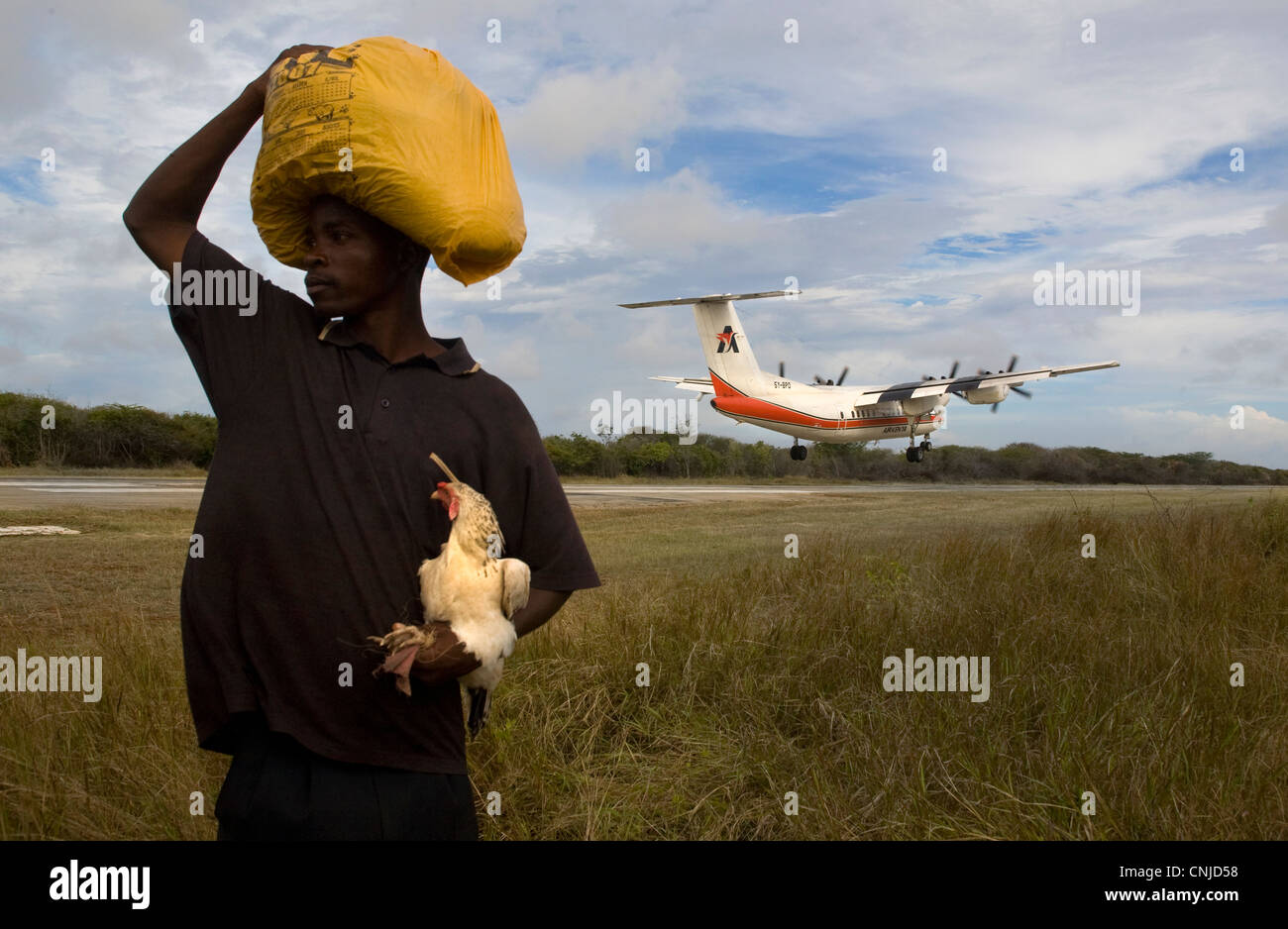 A man holds a chicken as an Air Kenya plane lands on Manda island ...