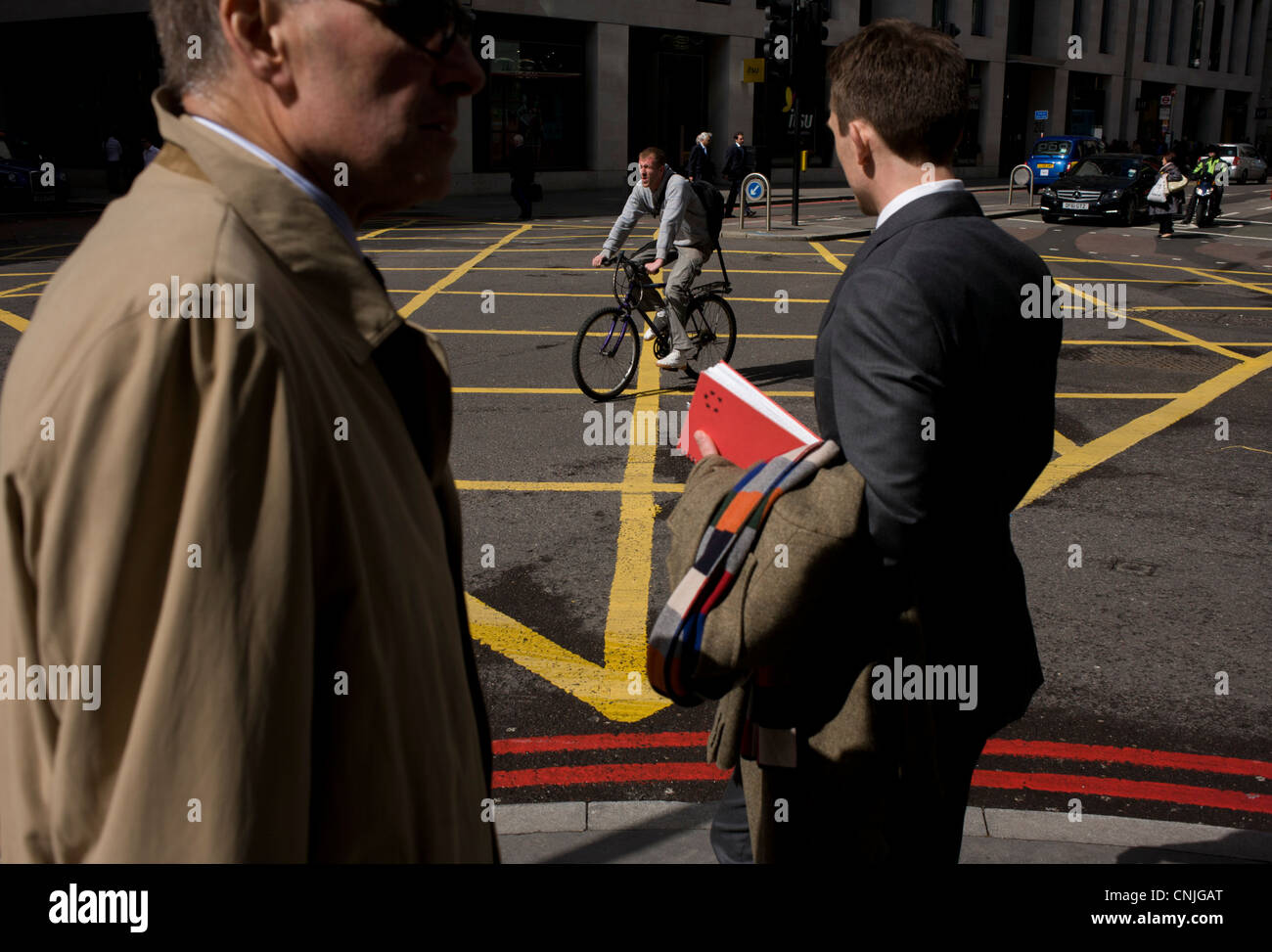 Pedestrians and cyclist who rides over a yellow box junction grid in a ...