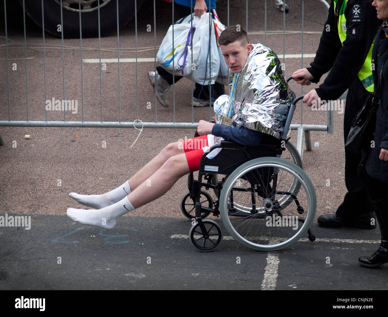 A runner with severe exhaustion is wheeled off for medical assistance ...