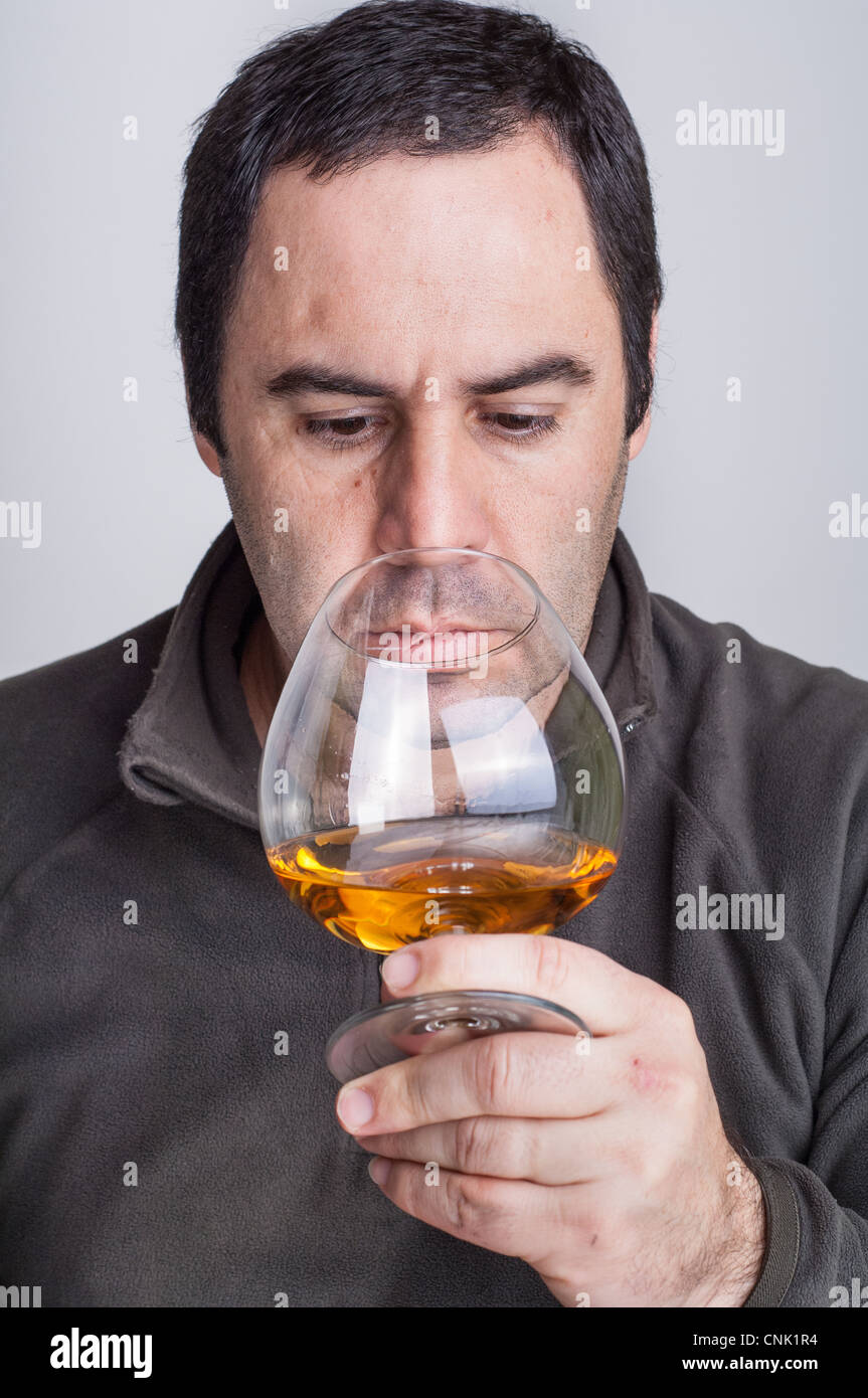 Handsome man sniffing a glass of whiskey Stock Photo - Alamy